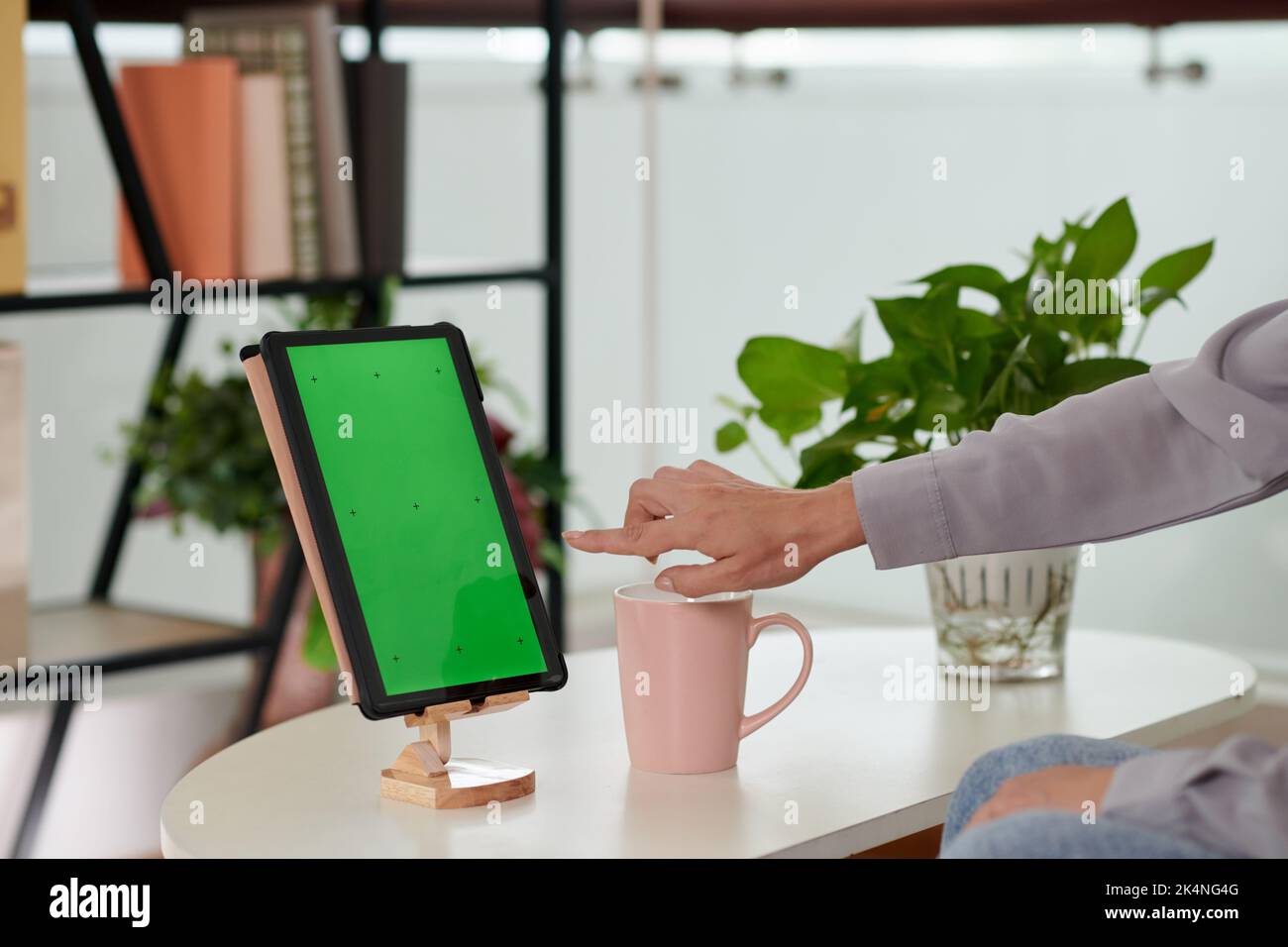 Hand of young female home office worker pointing at green screen of ...