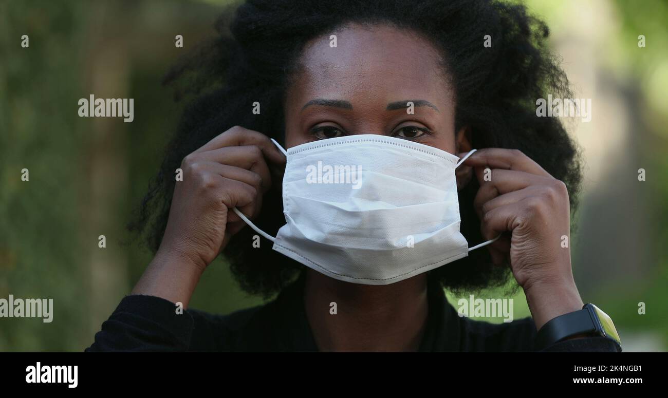 Black woman putting covid-19 face mask outside looking at camera Stock ...