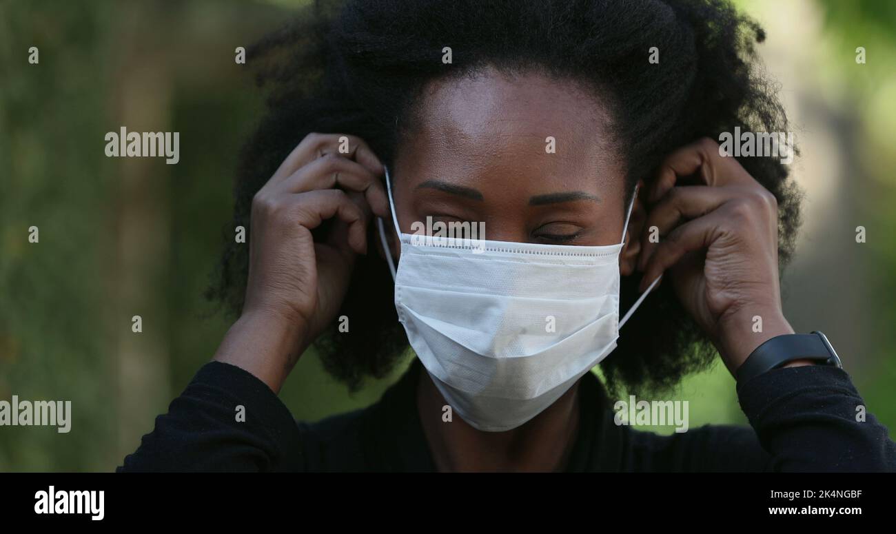 Black woman putting covid-19 face mask outside looking at camera Stock ...