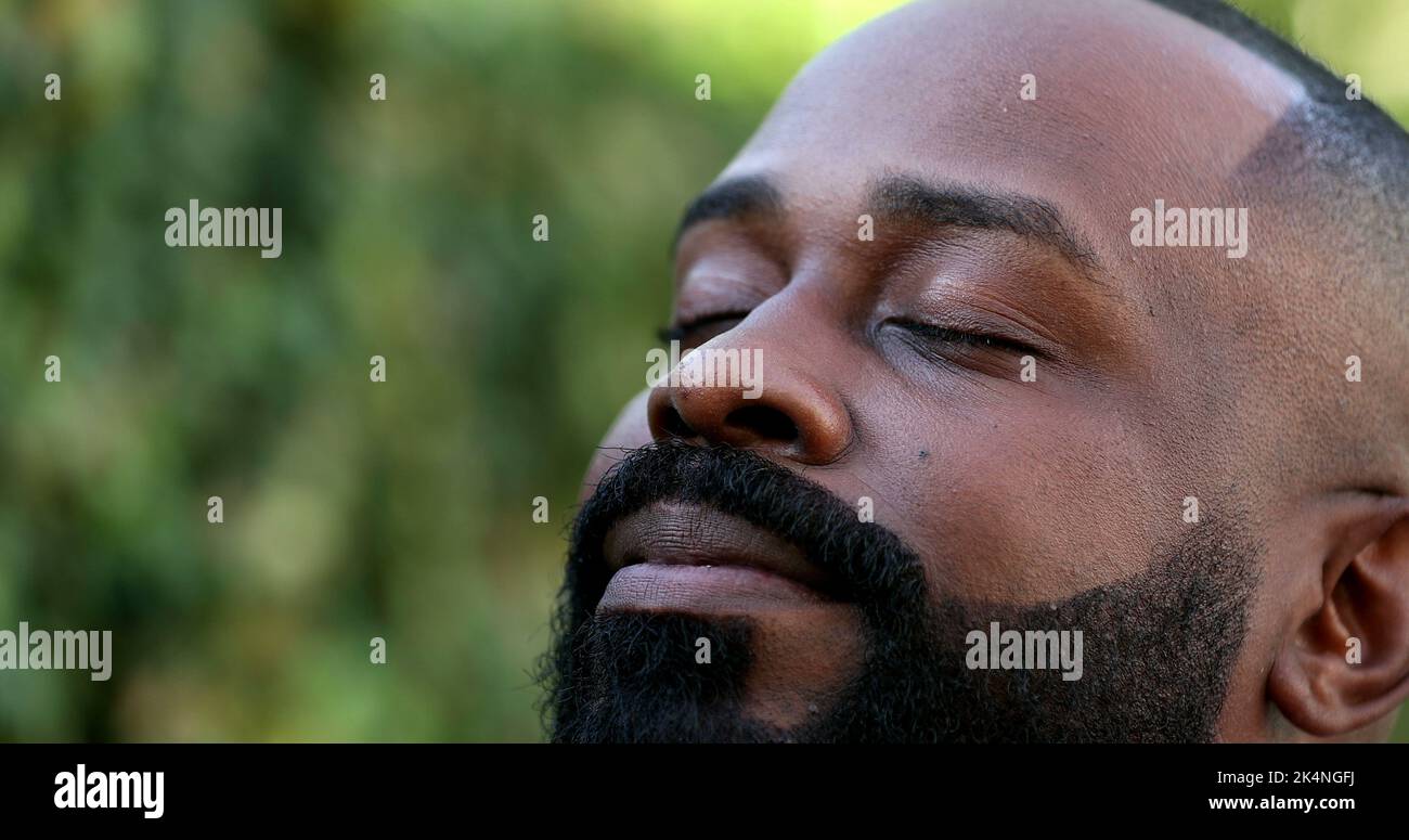 Positive African breathing fresh air outside, happy close-up face ...