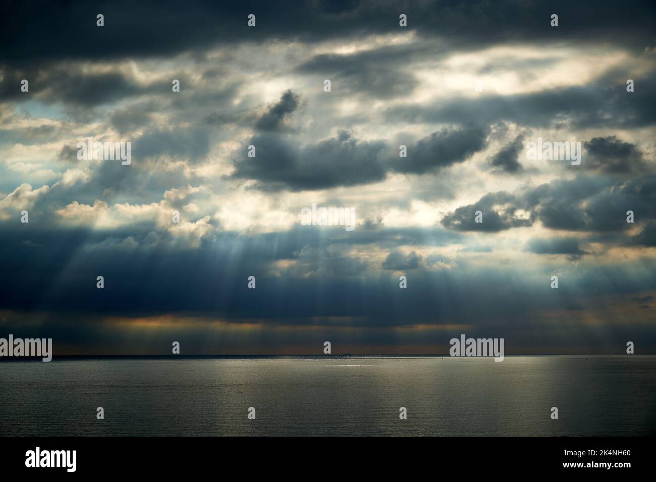 A dramatic sky over the sea with rays of light coming through the ...
