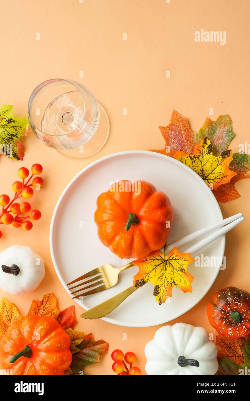 Autumn table setting. White plate, golden cutlery and fall decorations ...