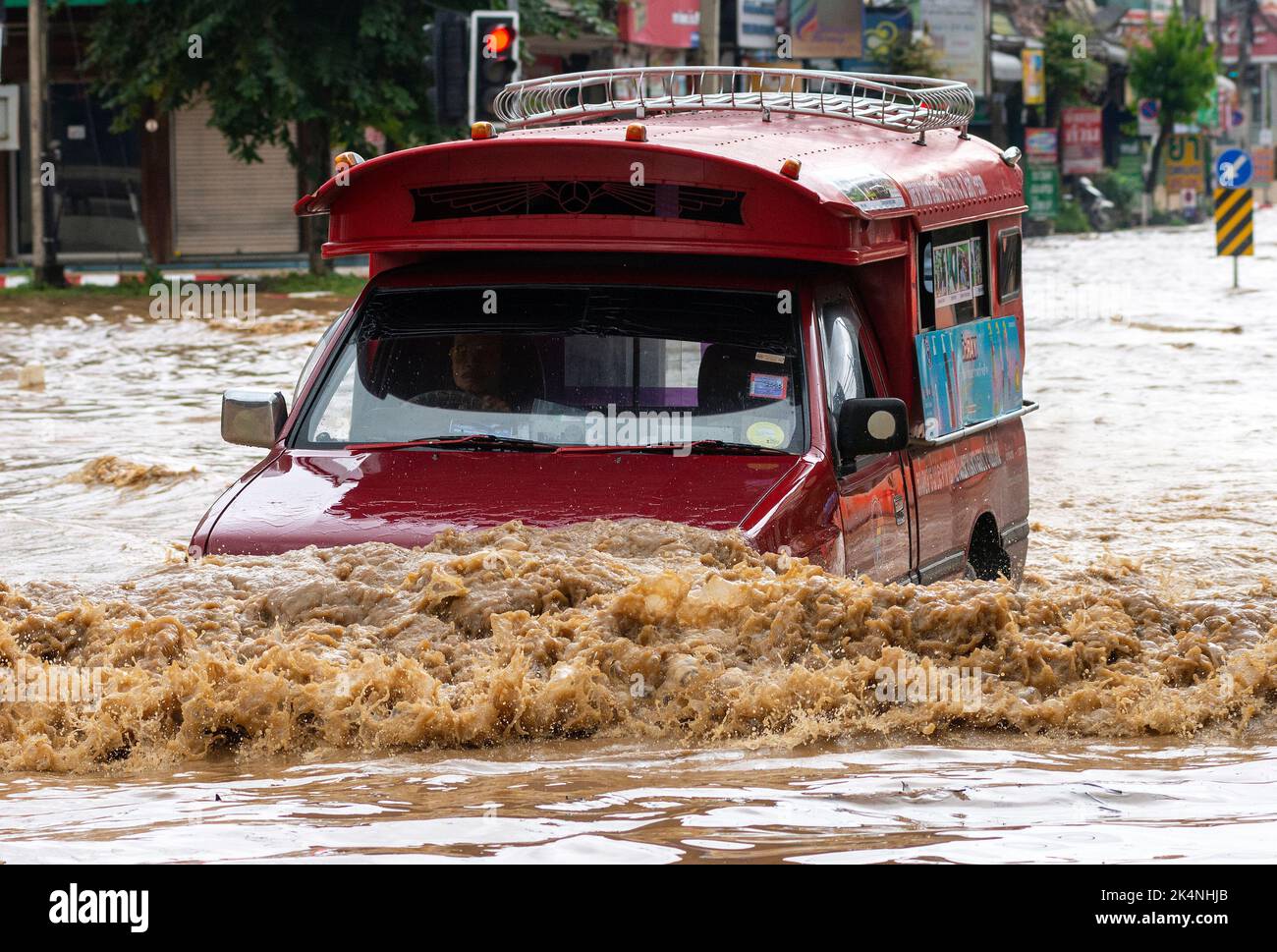 A taxi driver wade through floodwaters during flooding as Ping River ...