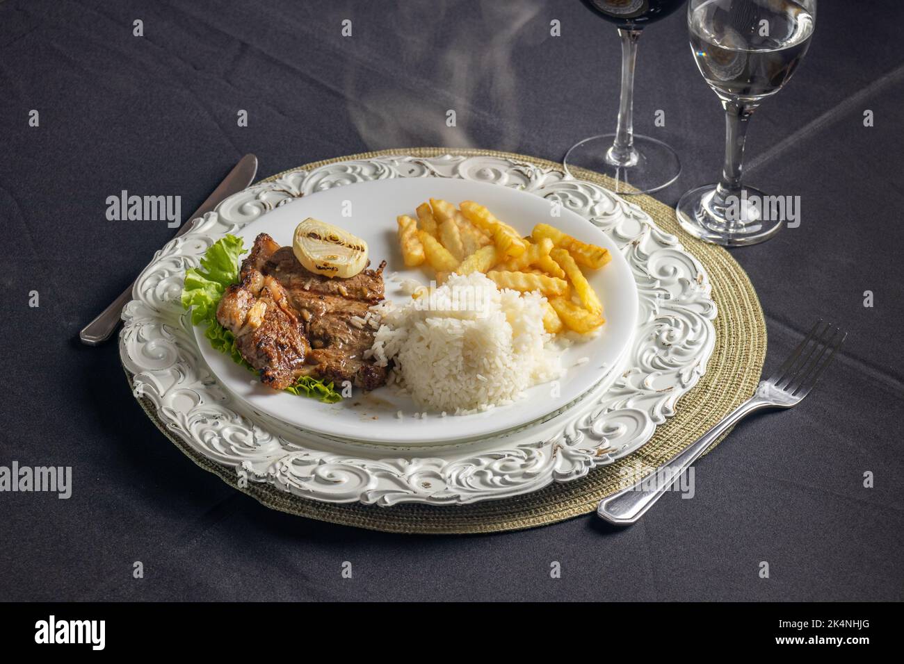 A close-up shot of a dish with rice french fries and steak served on ...