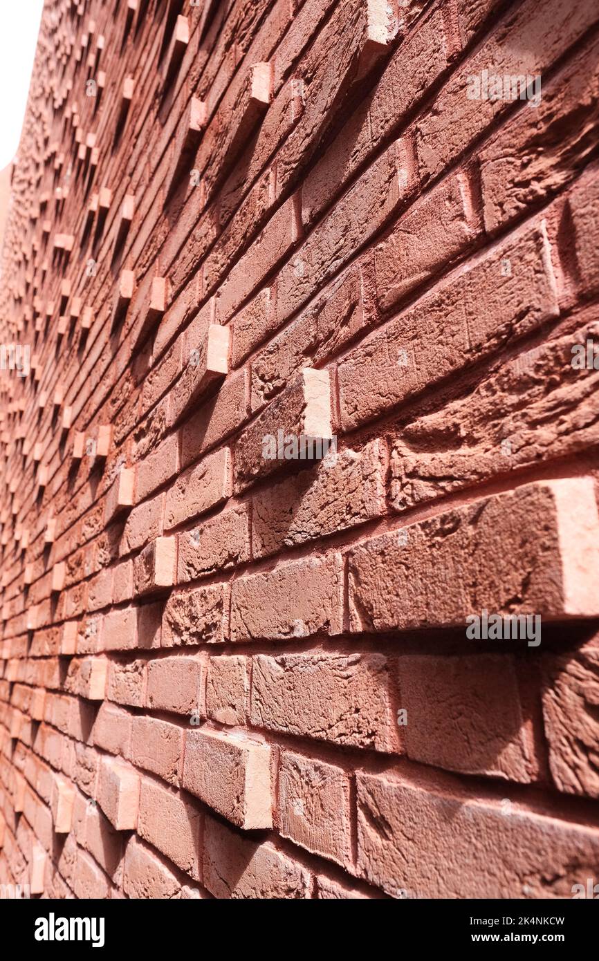 A vertical closeup of a red-brick wall with a special design of ...