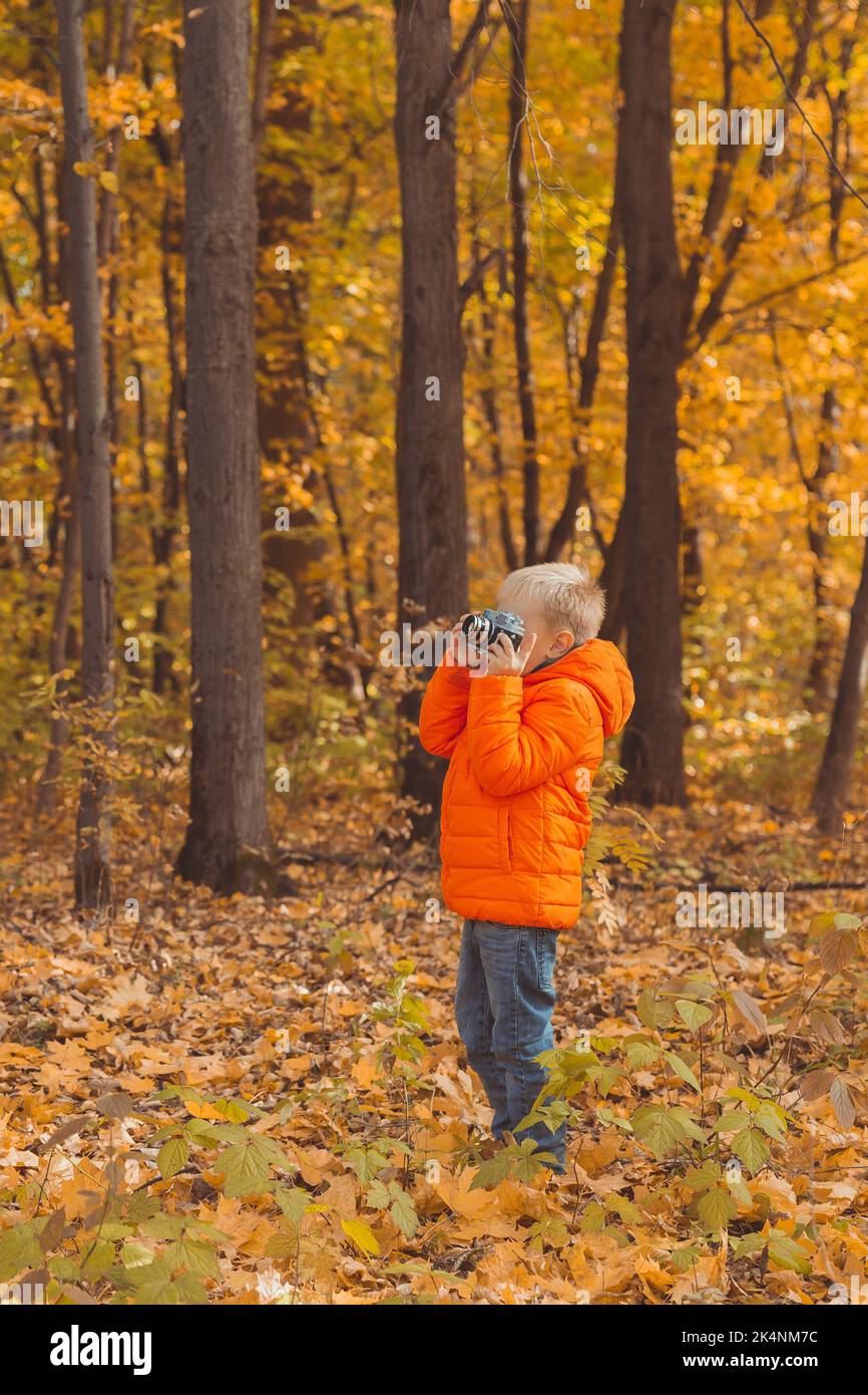 Boy with retro camera taking pictures outdoor in autumn nature. Leisure ...