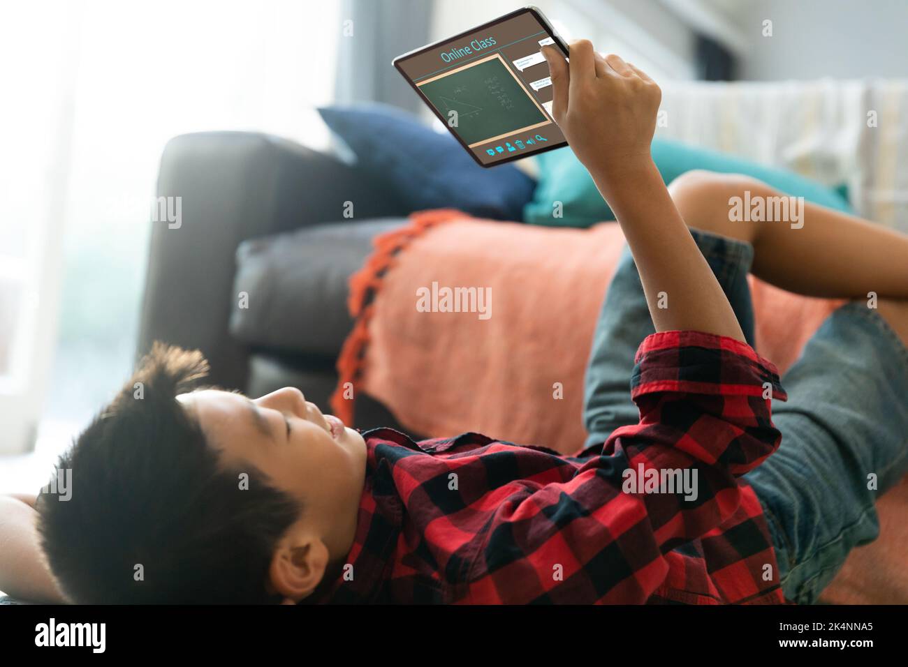 Asian boy using tablet for video call, with class on screen ...