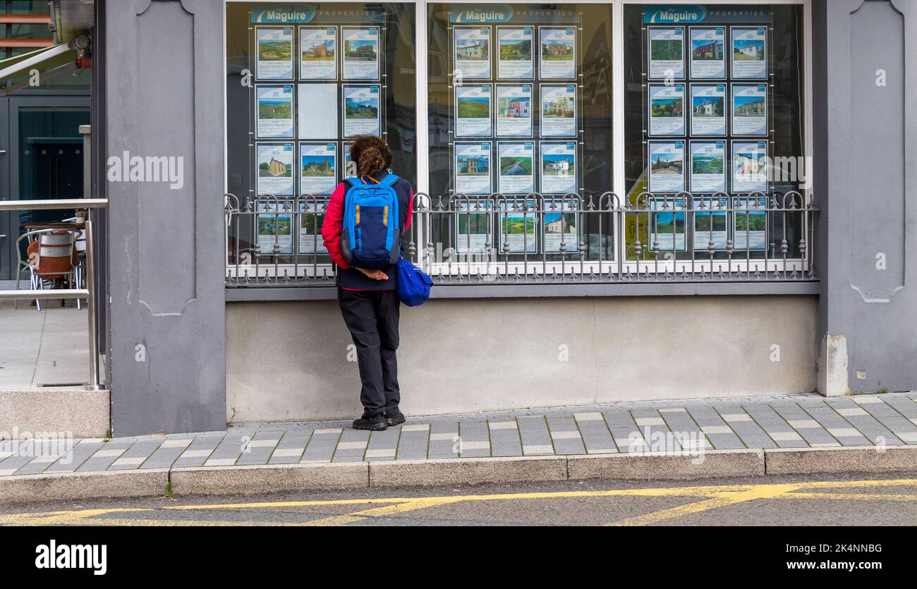 Female looking at Estate Agents window checking house prices or ...