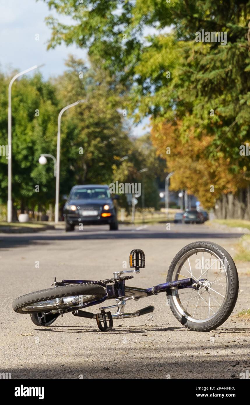 A bicycle lies on the road after a car hit a cyclist. In the background ...
