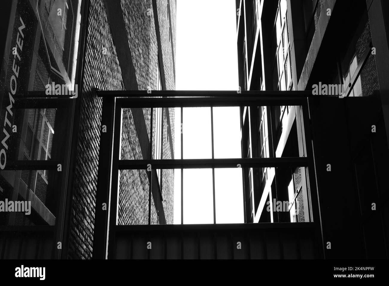 A grayscale of a metal gate between two building with a sign on the ...