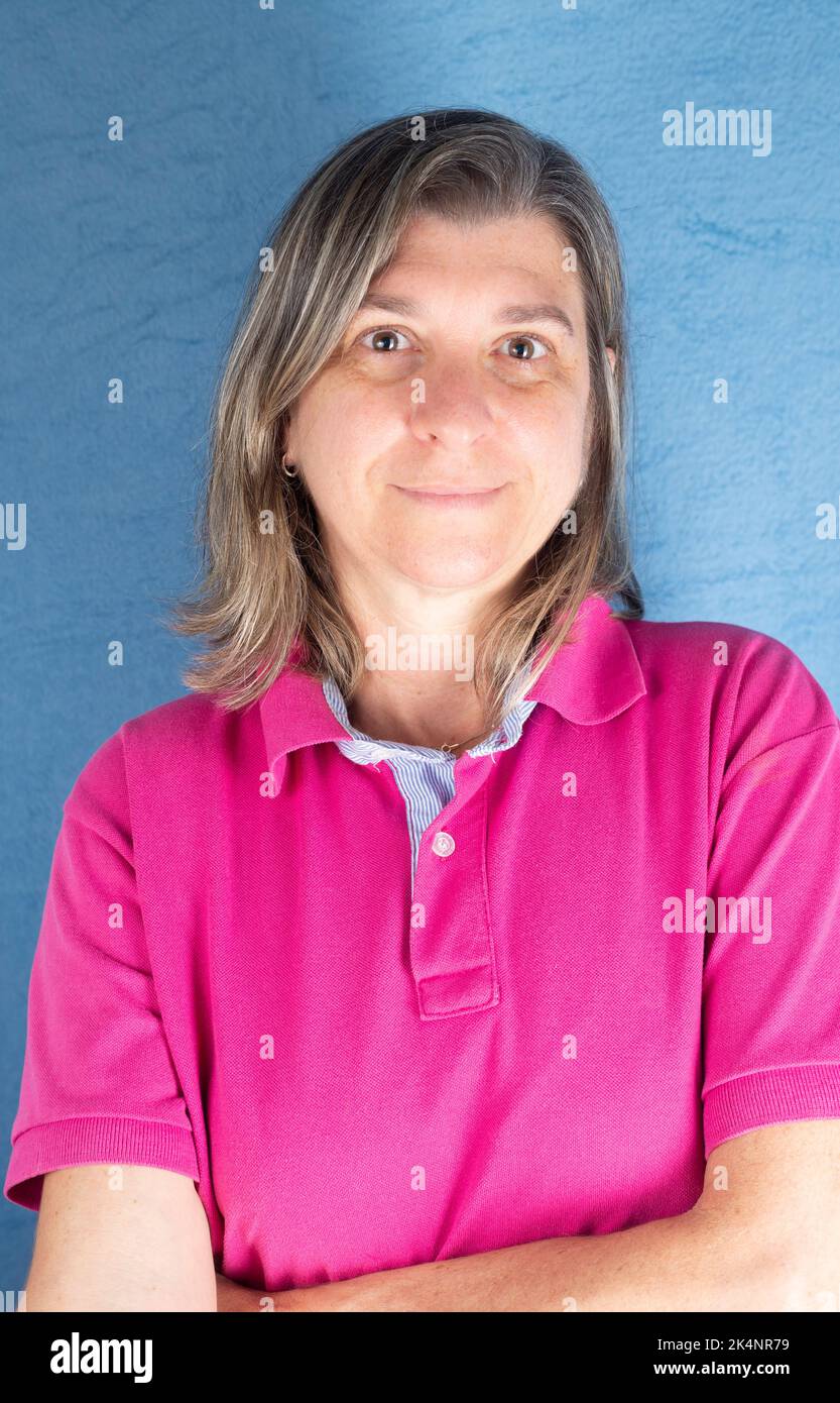 Studio portrait of Caucasian woman wearing pink shirt against blue ...