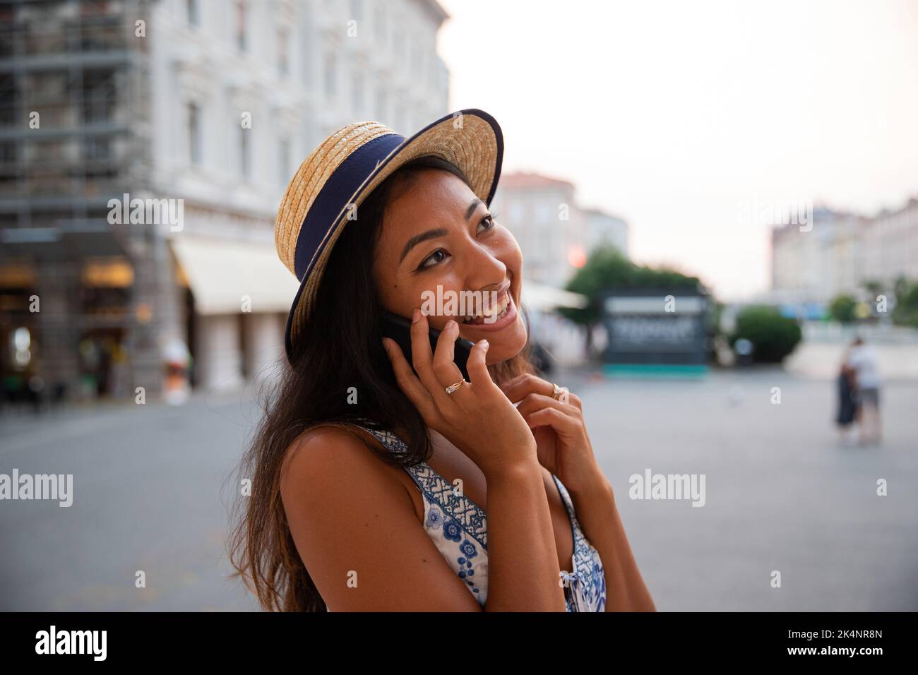 Smiling tourist chats joyfully on the phone during her walk in the city ...
