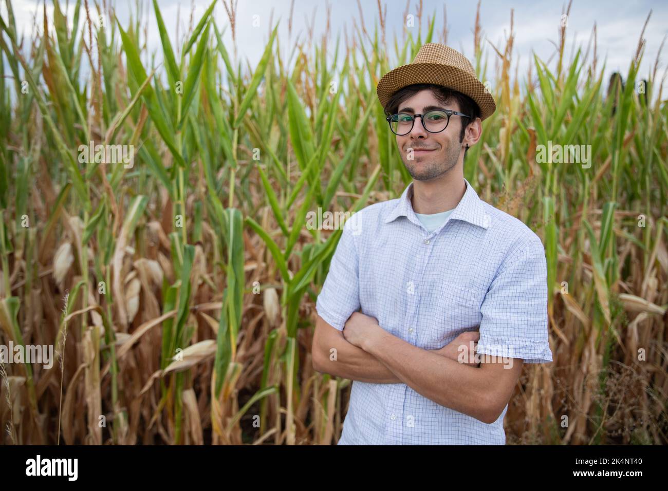 Smiling farmer with his hands crossed in front of his corn field, soon ...