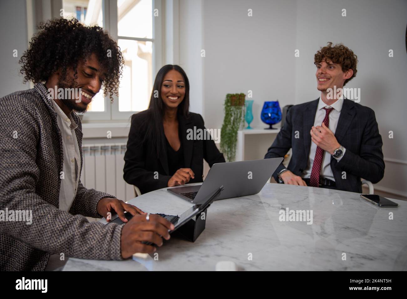 Multiracial colleagues sitting around the table in the office discuss ...