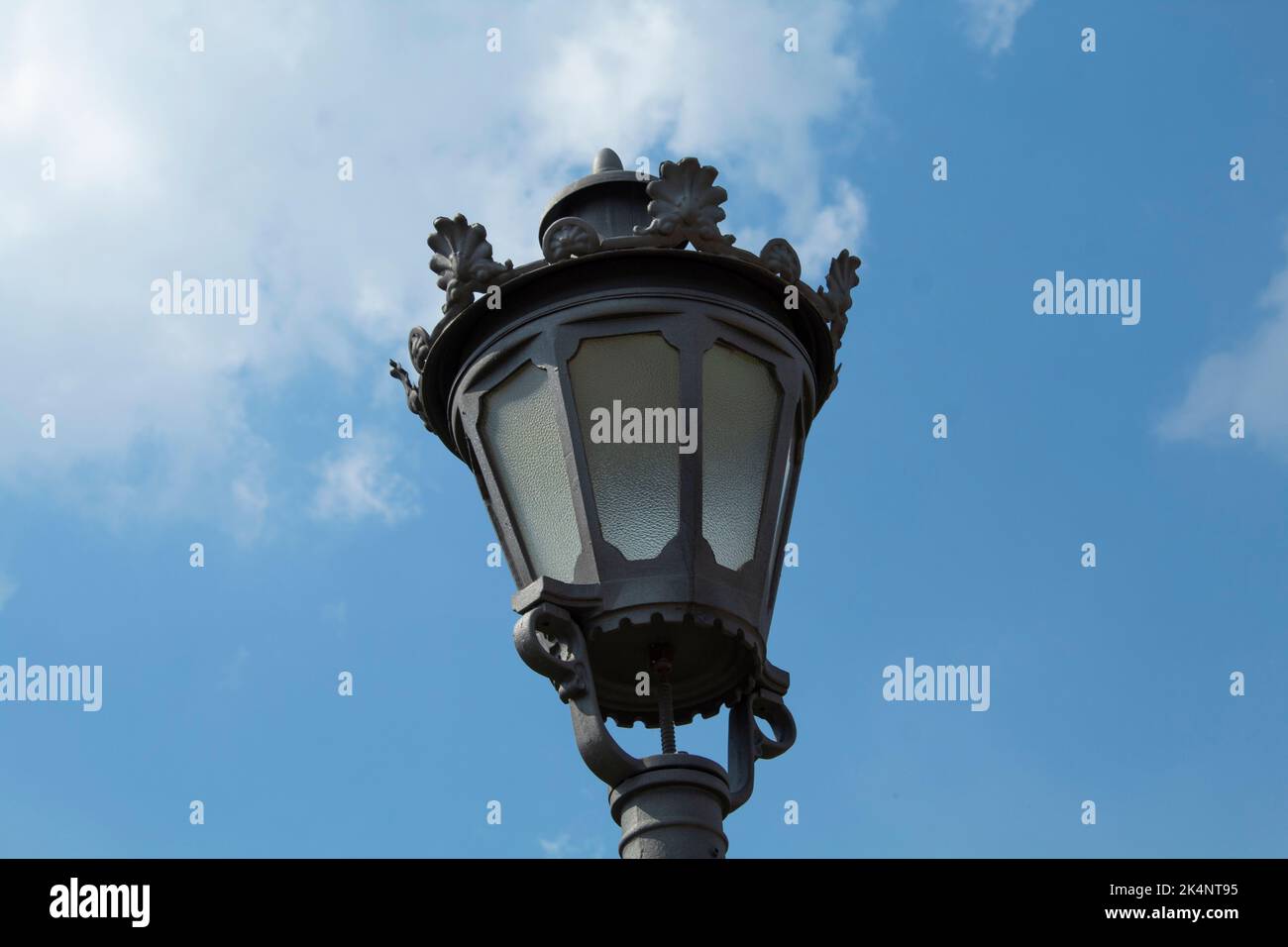 Vintage style street lamp top isolated on blue sky with clouds. Retro ...