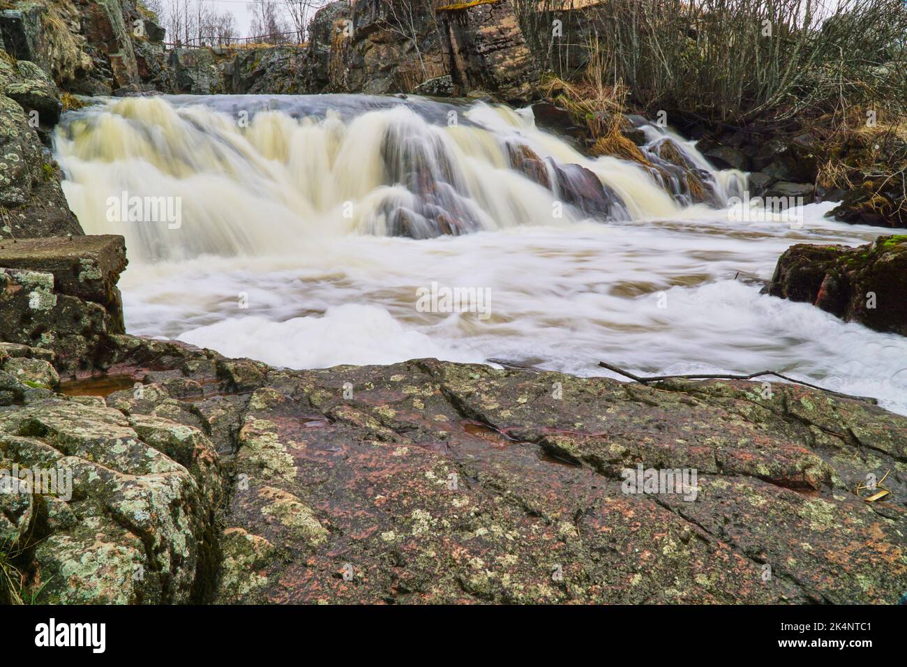 A long exposure shot of a waterfall flowing over rocks in a forest ...