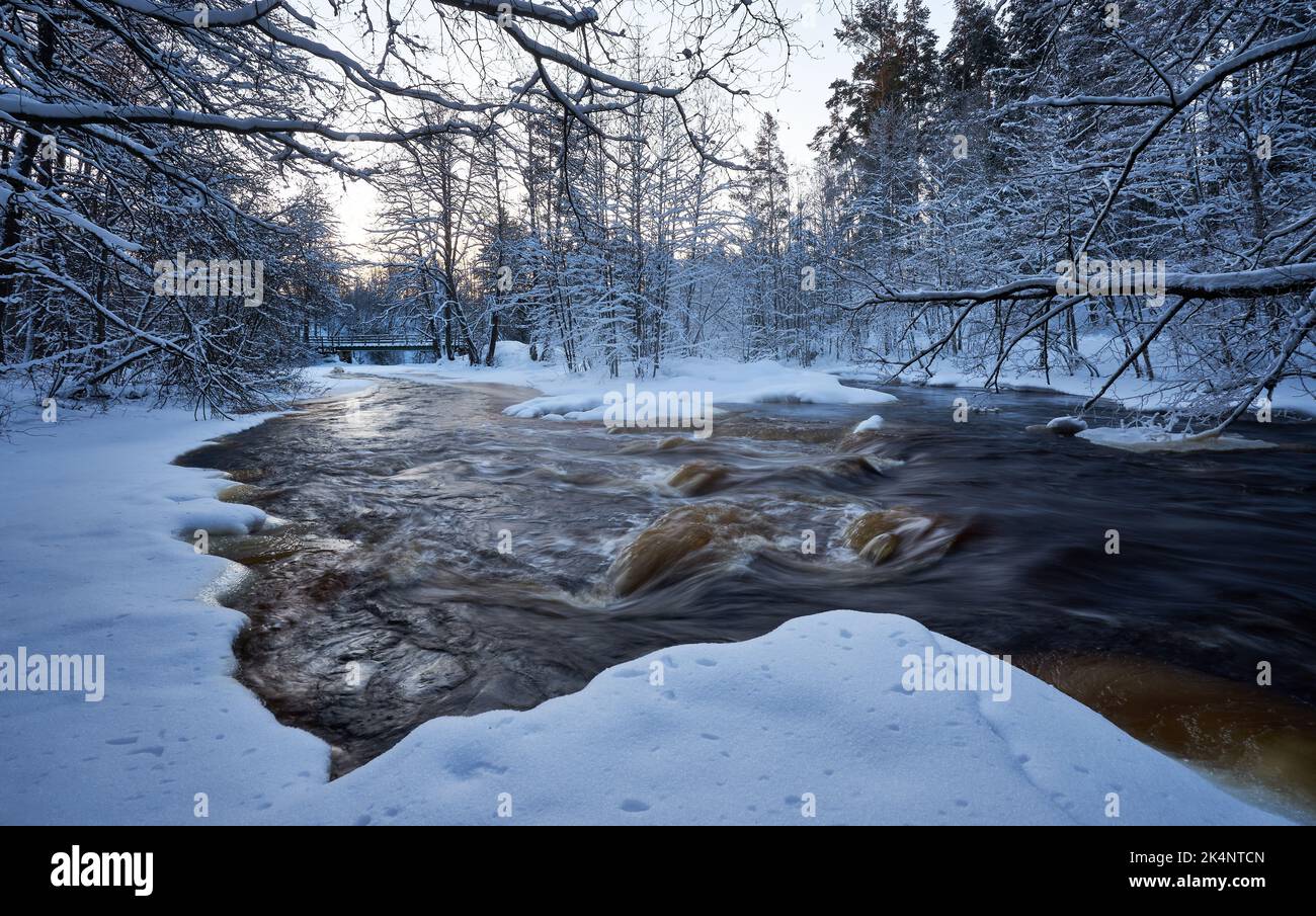 A long exposure shot of a river flowing over rocks in a forest covered ...