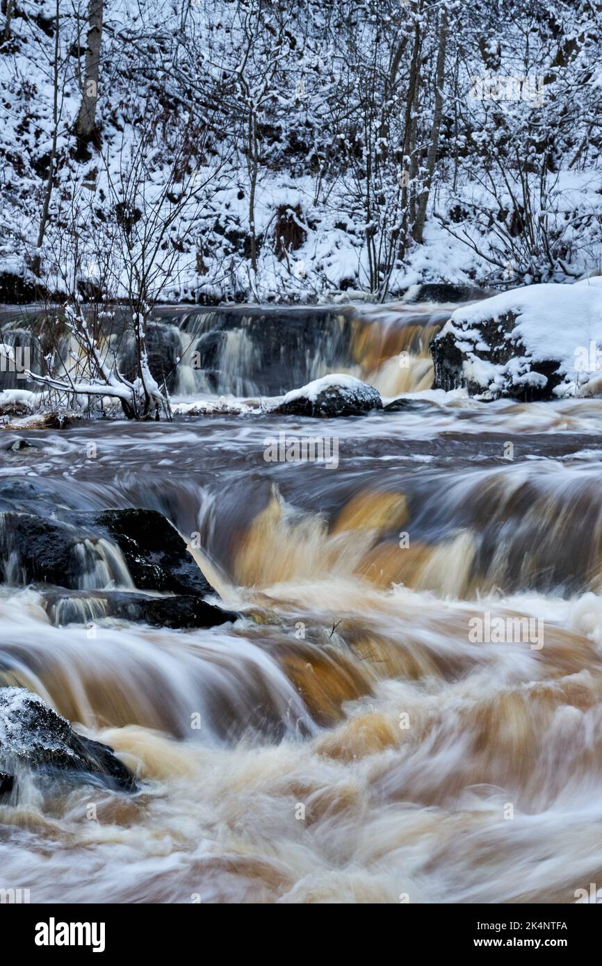 A long exposure shot of a waterfall flowing over rocks in a forest ...