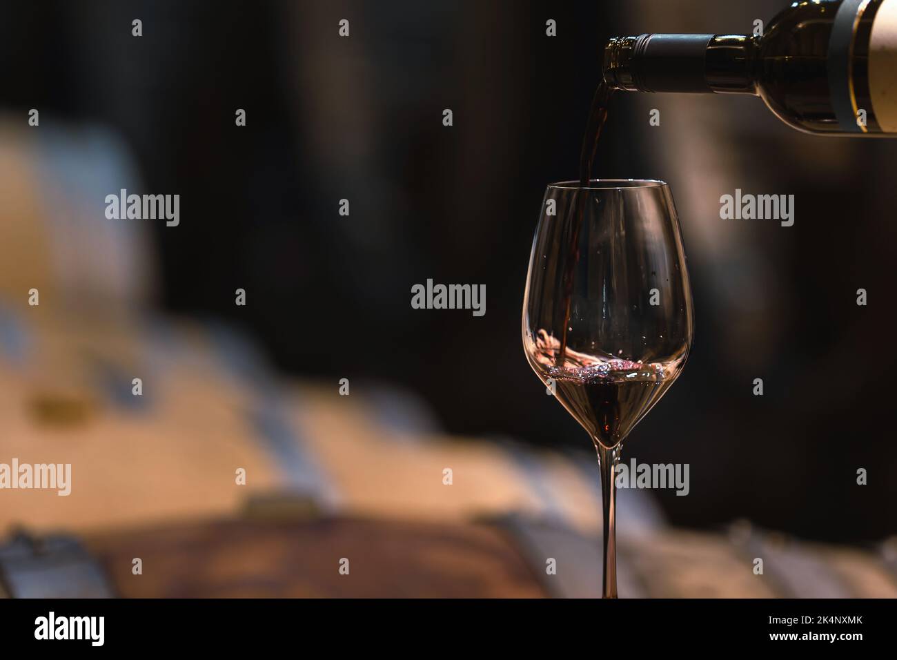 Hands pouring red wine from a bottle into a glass in authentic wine ...