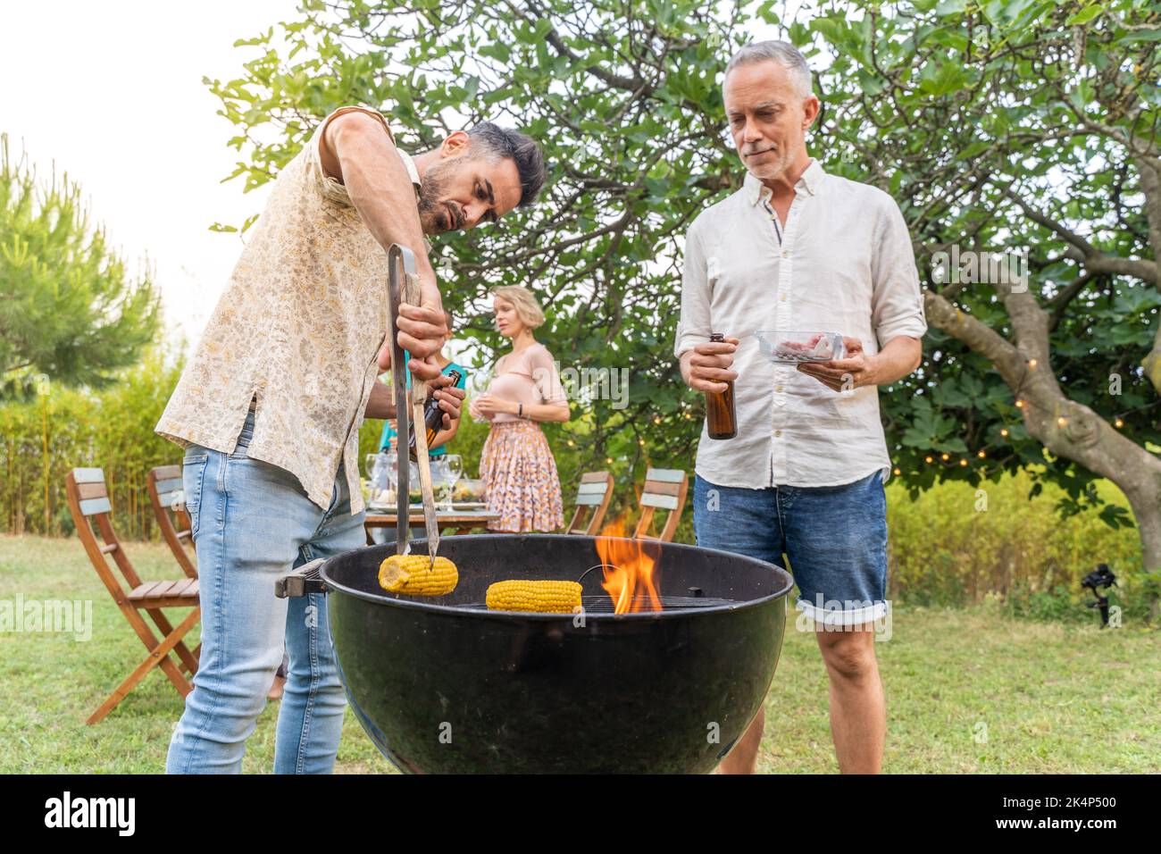 Multiethnic middle-aged people cooking with the barbecue smiling happy ...