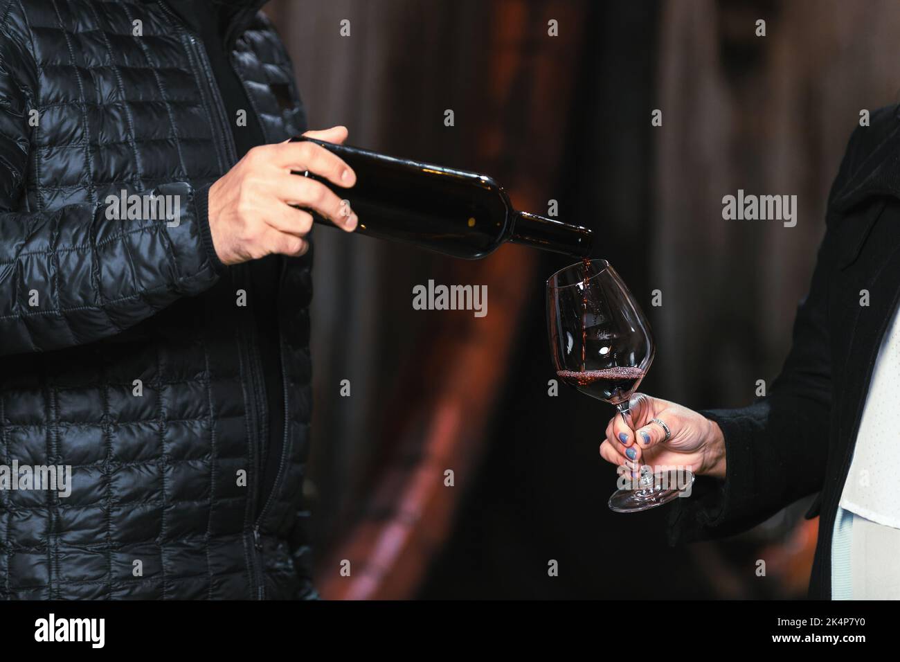 Man pouring fine red wine to a charming woman, in front of a large old ...