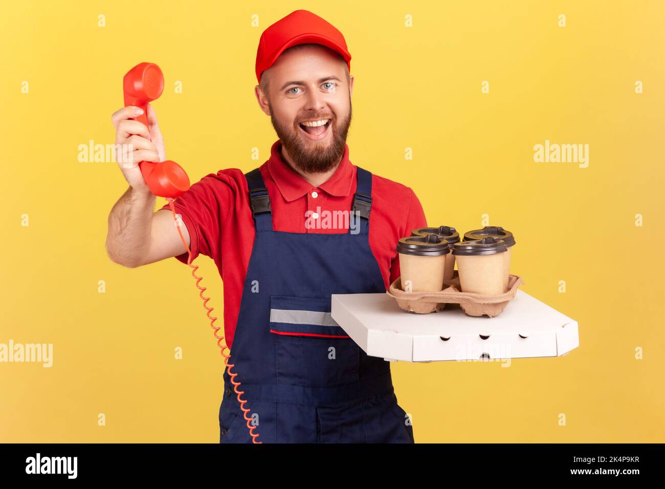 Portrait of delivery man in blue overalls red t-shirt and cap holding ...