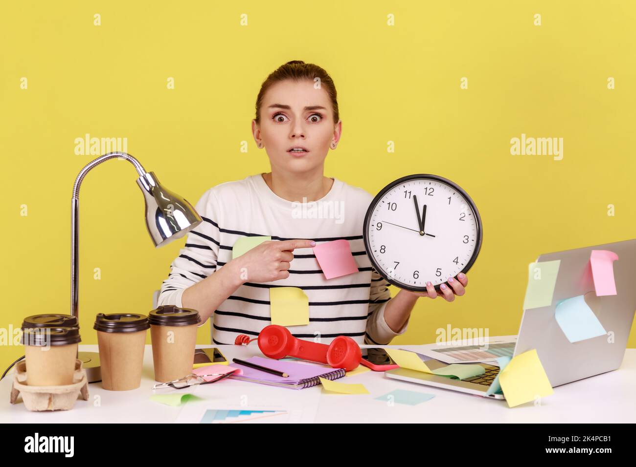 Serious shocked woman office worker pointing finger at big wall clock ...