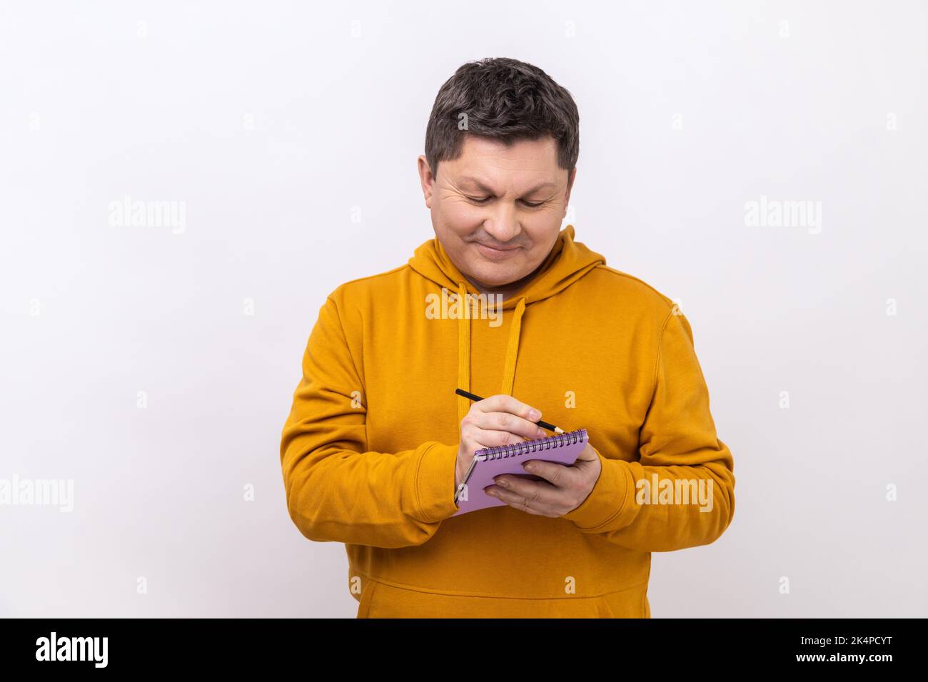 Portrait of happy positive man making notes with pen at notepad ...