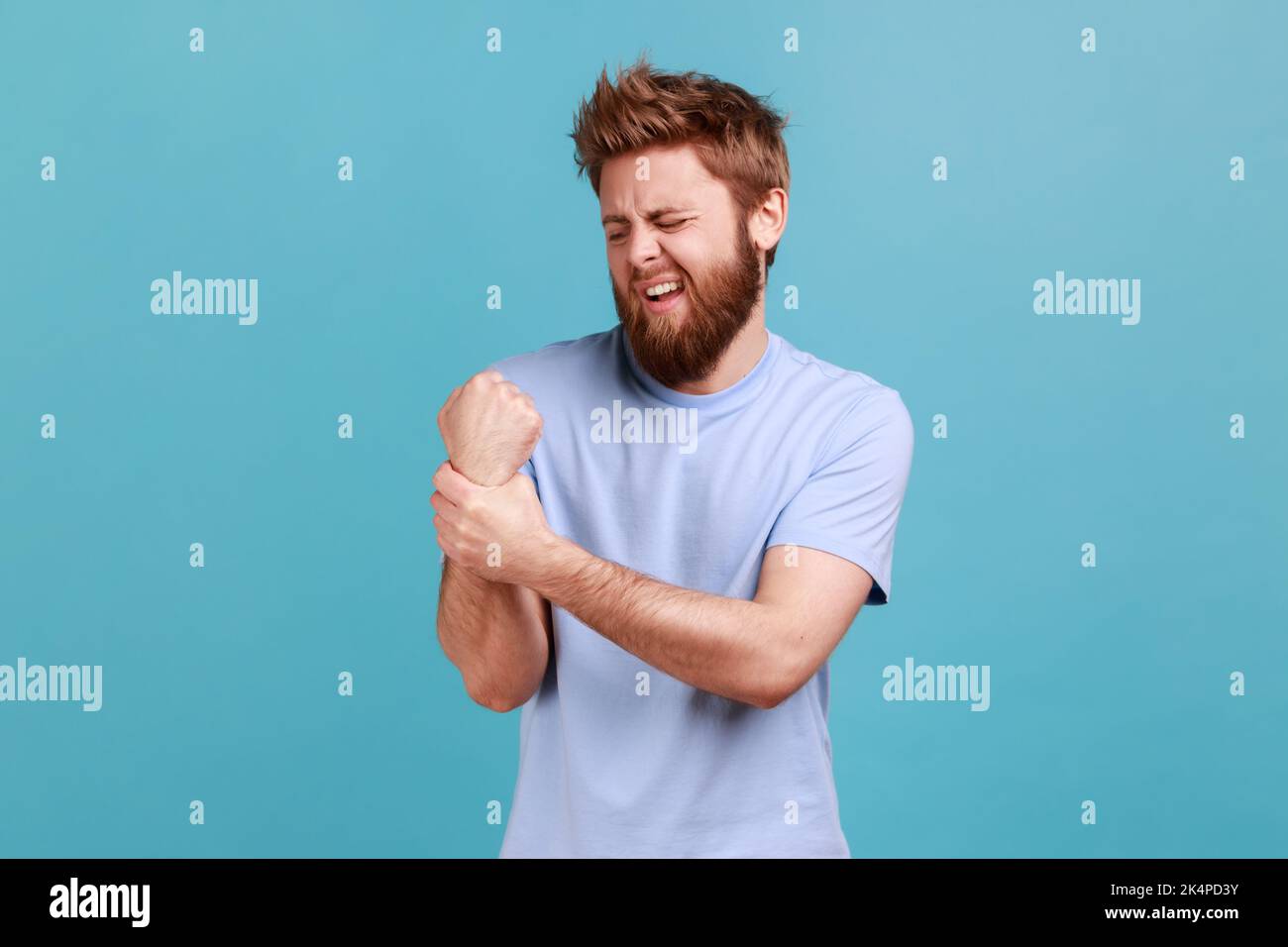 Portrait of unhealthy sick young adult bearded man massaging wrist ...