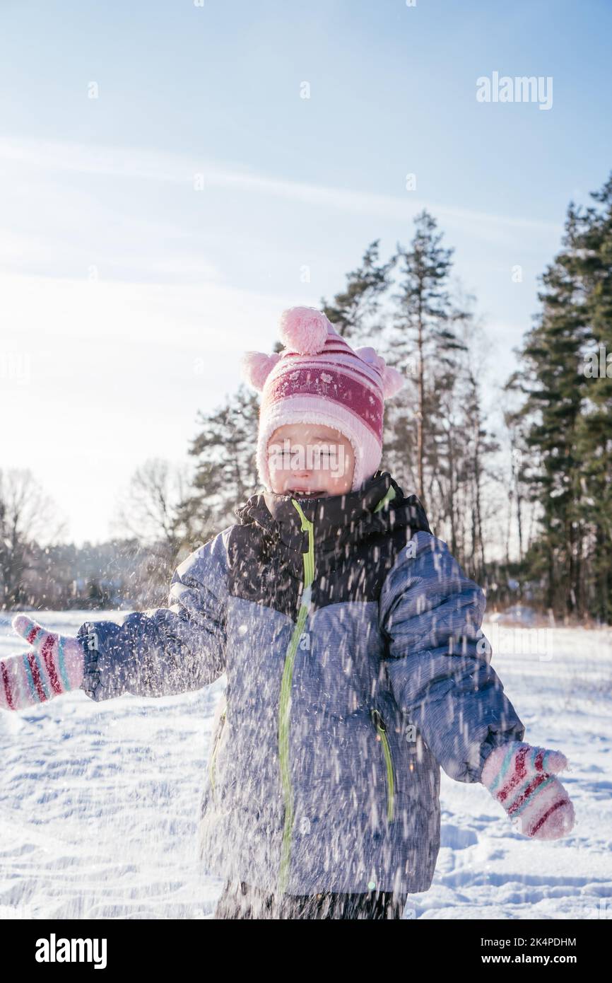 Little girl 3-4 years old in winter overalls, hat and mittens, stands ...