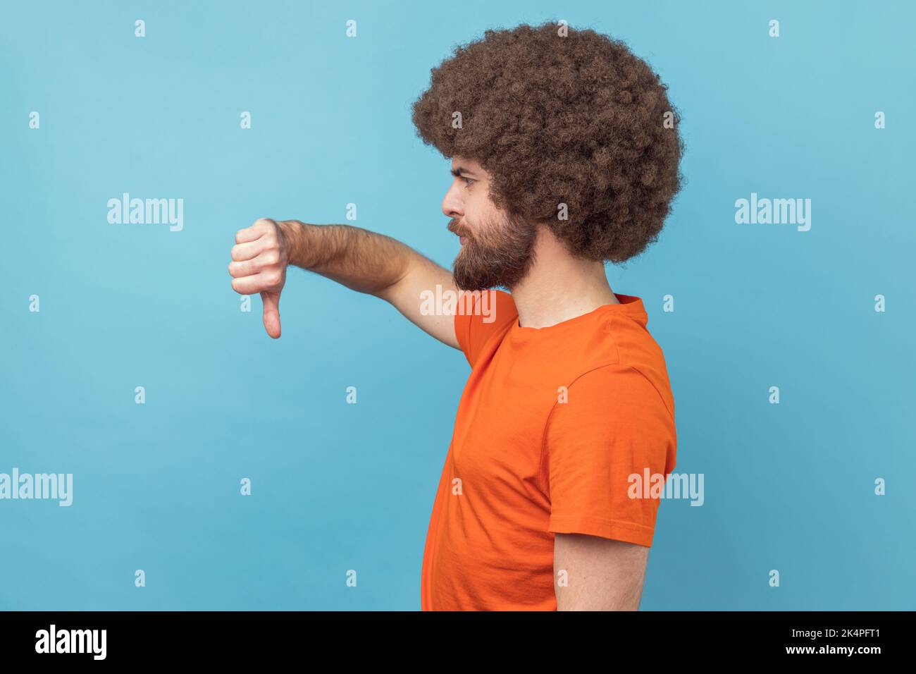 Side view of displeased man with Afro hairstyle wearing orange T-shirt ...