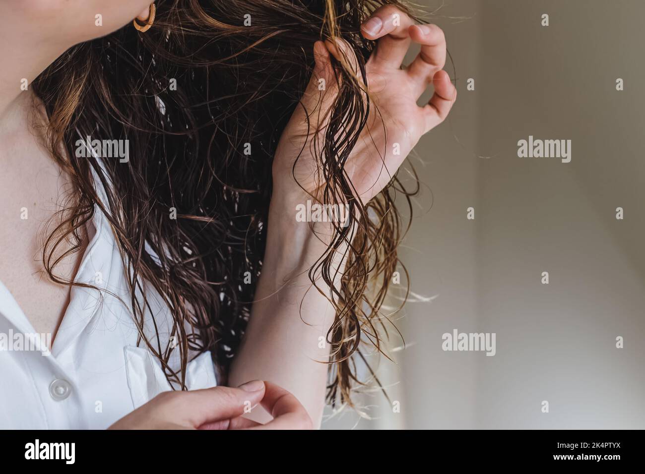 Close-up of feminine hand holding a strand of her wavy hair. Styling ...