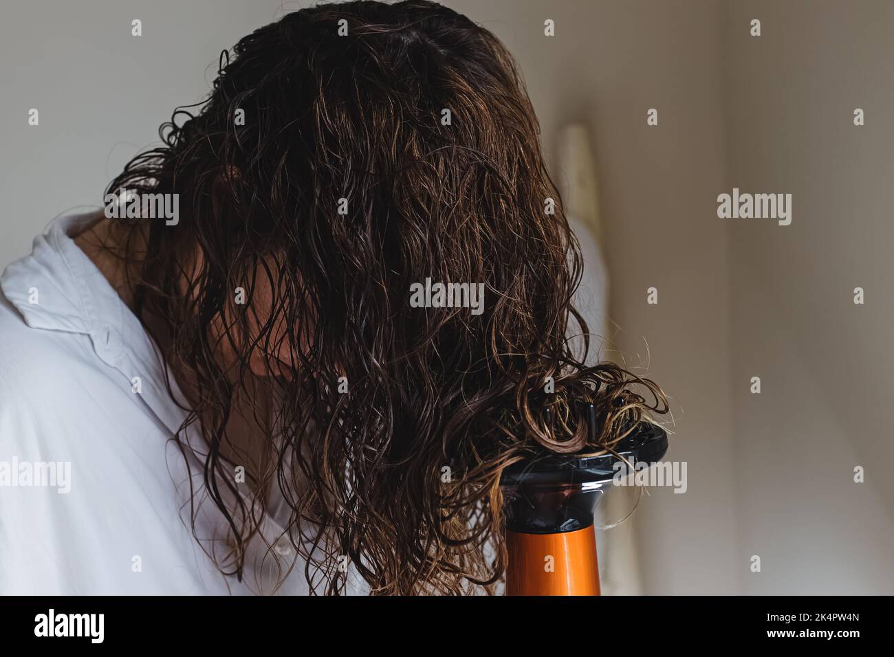 Woman diffusing her hair with a dryer. Drying hair according to a curly ...