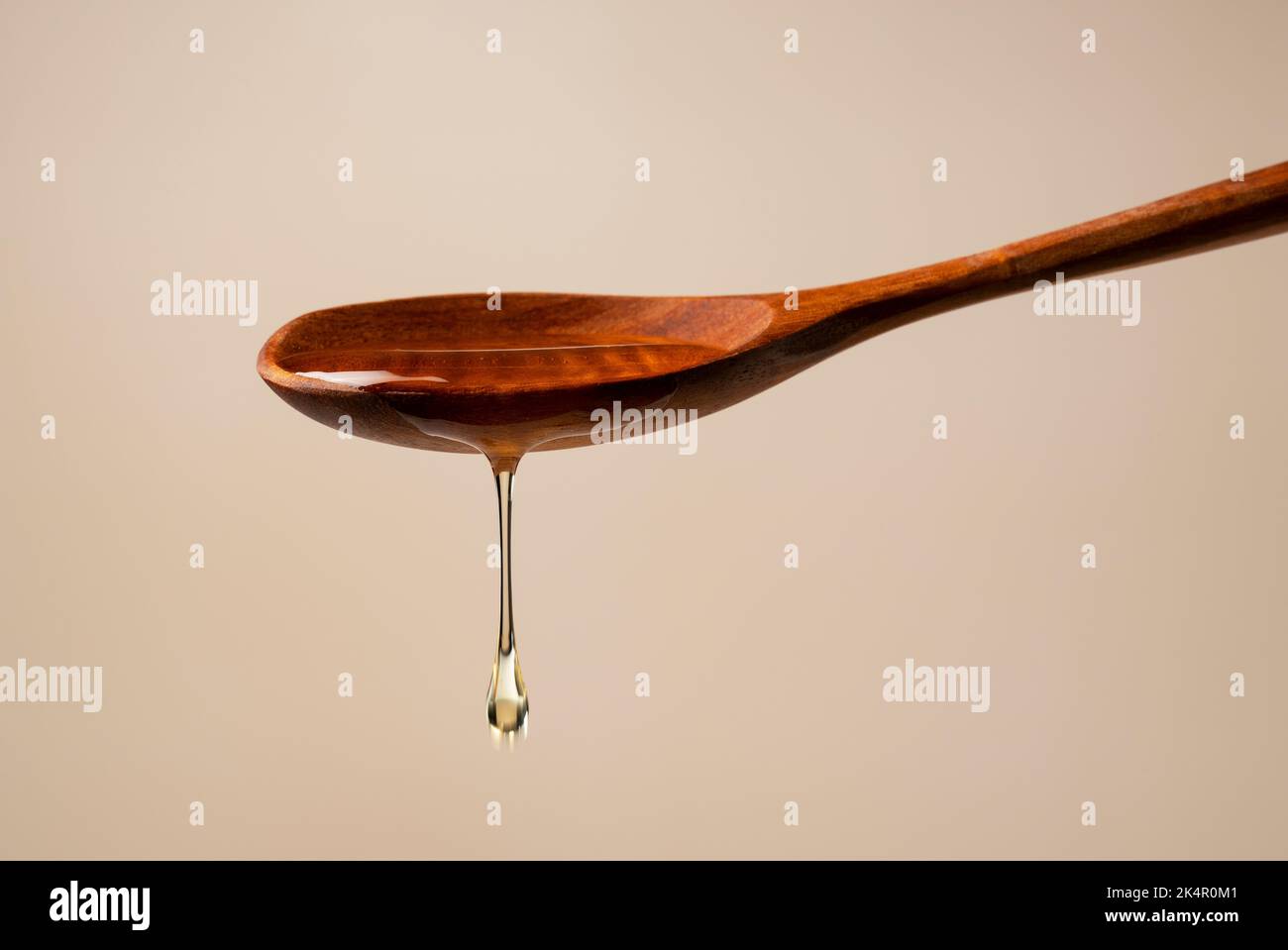 Honey and wooden spoon on beige background. Honey dripping from spoon ...