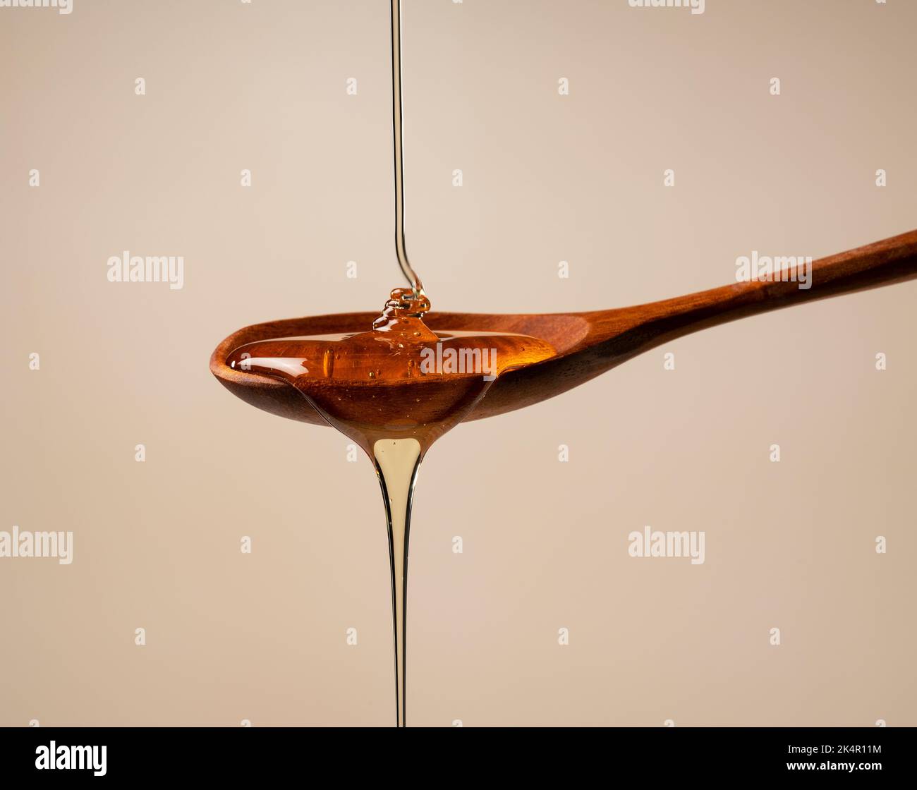 Honey and wooden spoon on beige background. Honey dripping from spoon ...