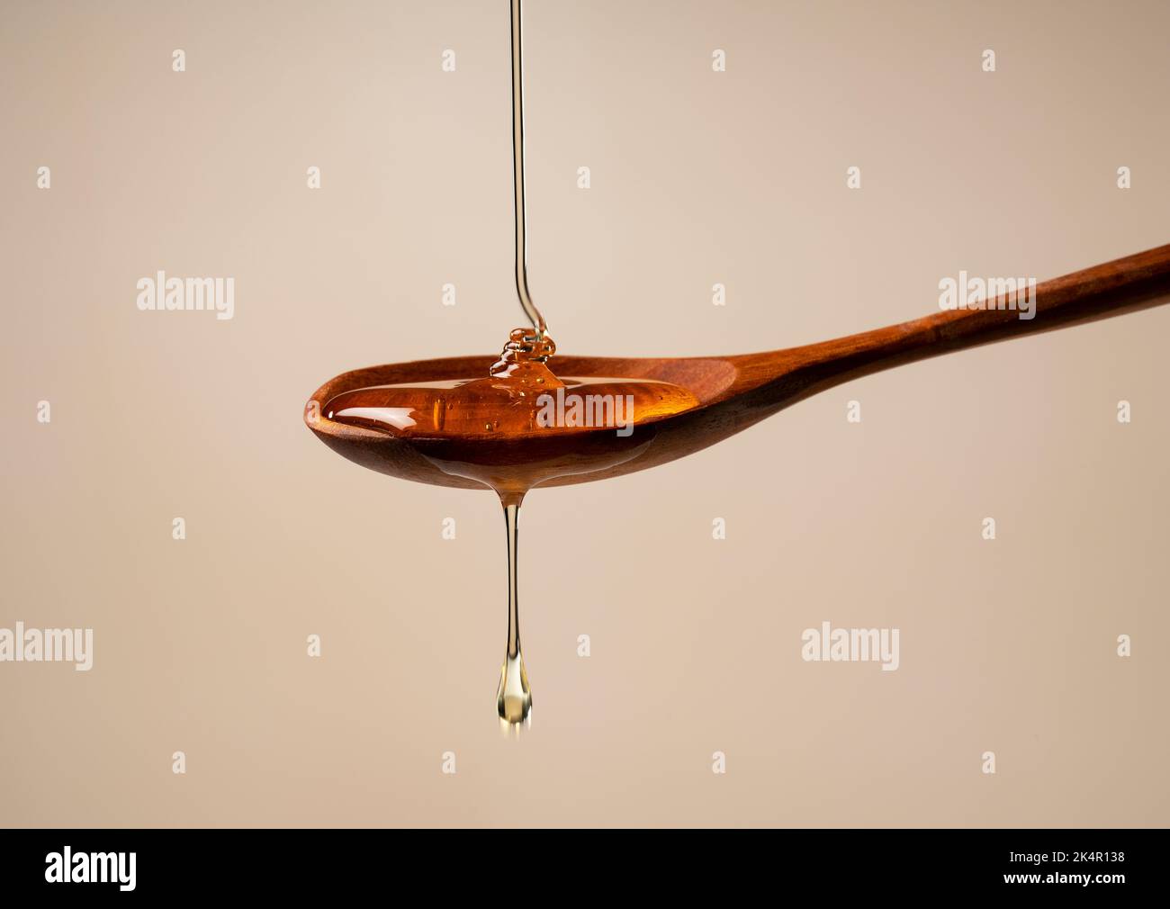 Honey and wooden spoon on beige background. Honey dripping from spoon ...