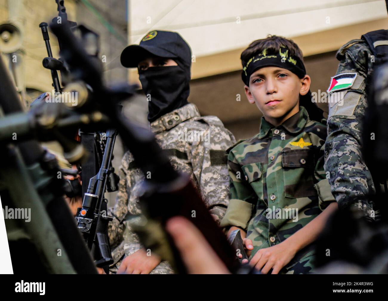 A Palestinian child stands among armed fighters from Saraya al-Quds ...