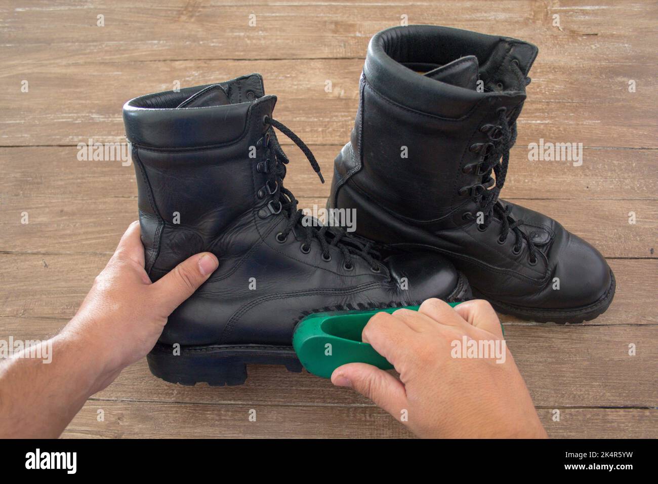 Image of the hands of a man who polishes a pair of military boots with ...