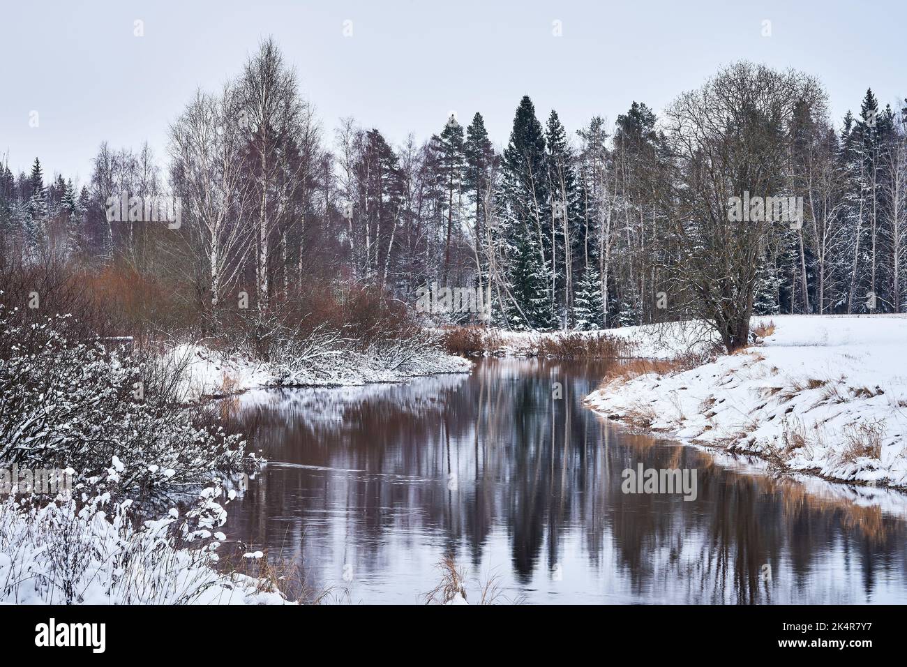 A beautiful river with a reflection of snowy conifers surrounding it ...