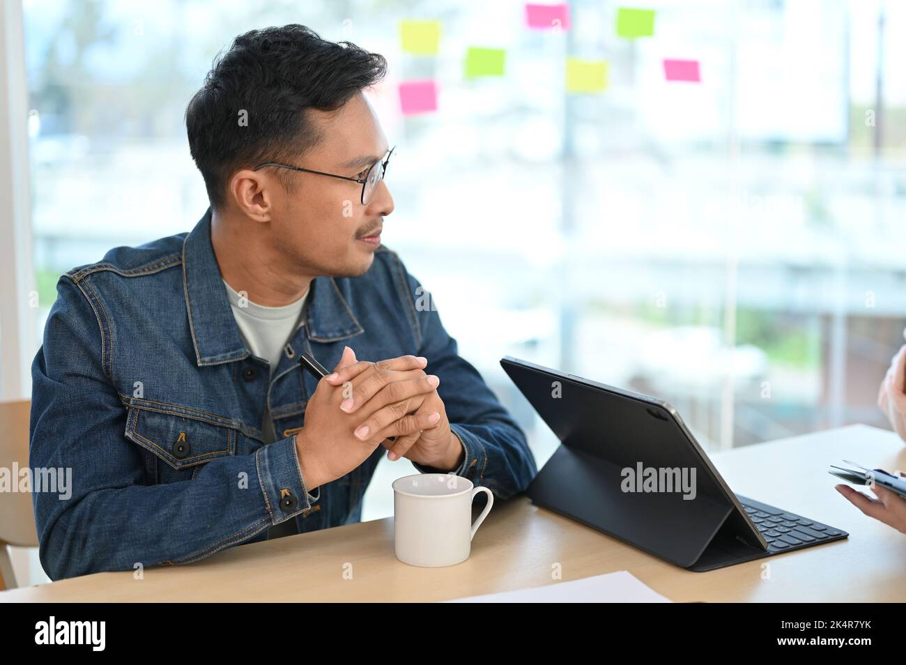 Smart and talented Asian male boss is concentrating on listening to his ...