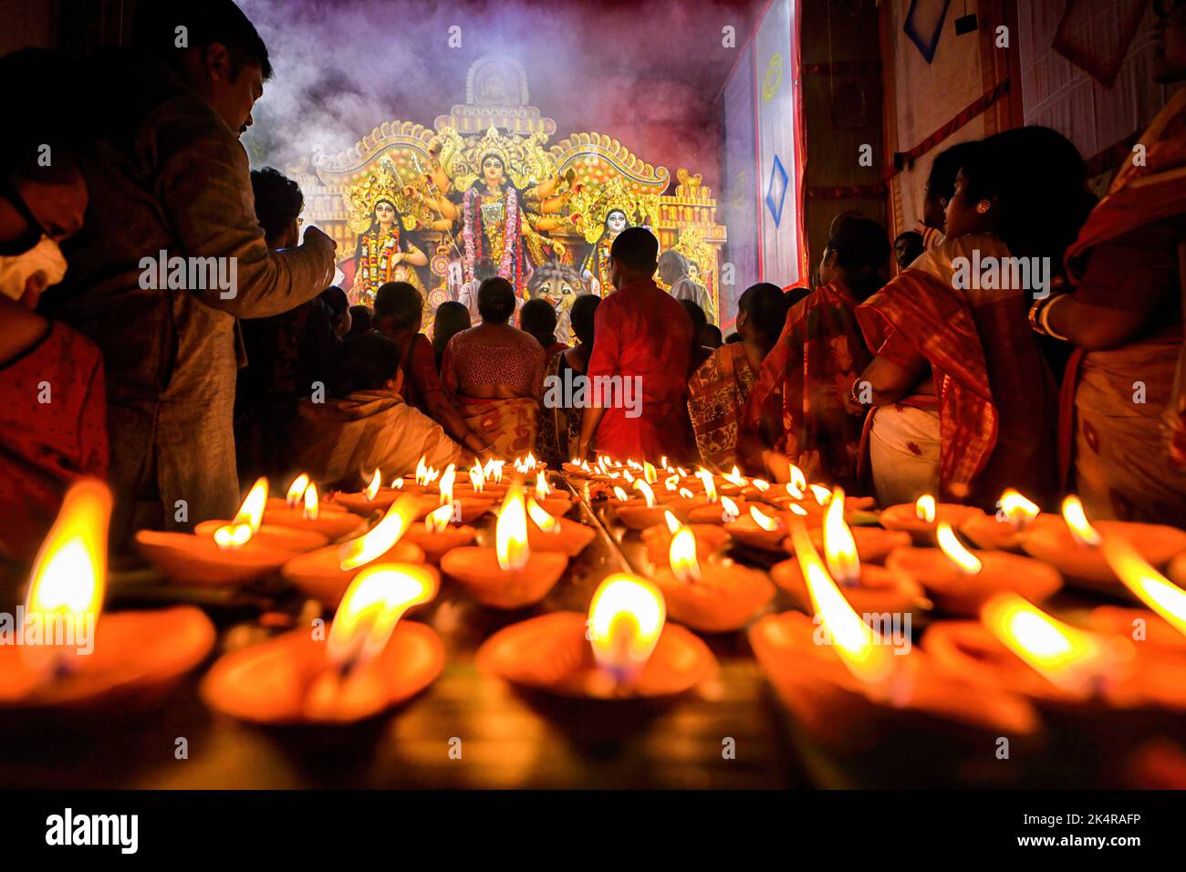 Hindu devotees light Diyas (clay lamps) in front of the idol of Lord ...
