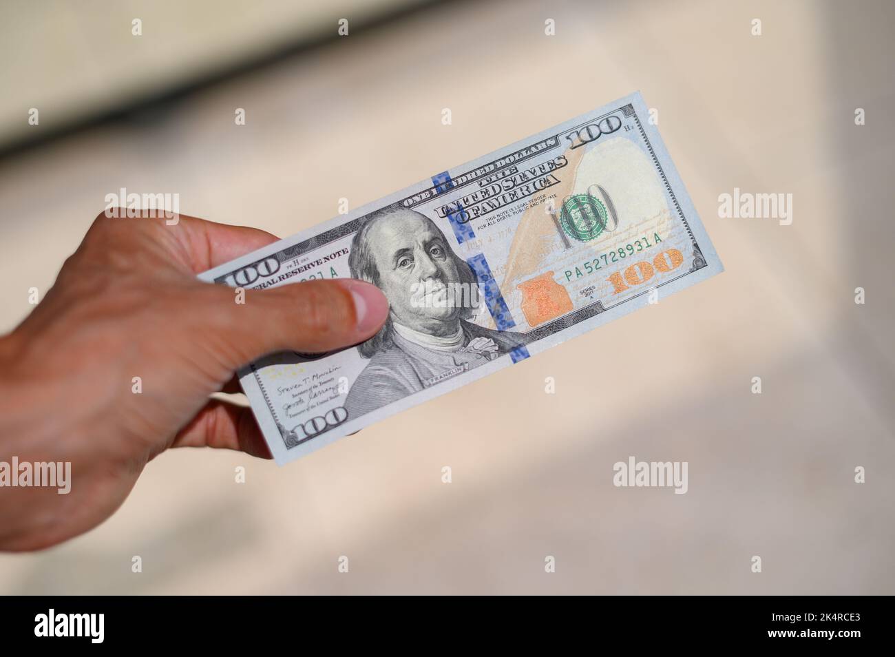 Close up 100 Dollar bank note in hand on grass background. One hundred ...