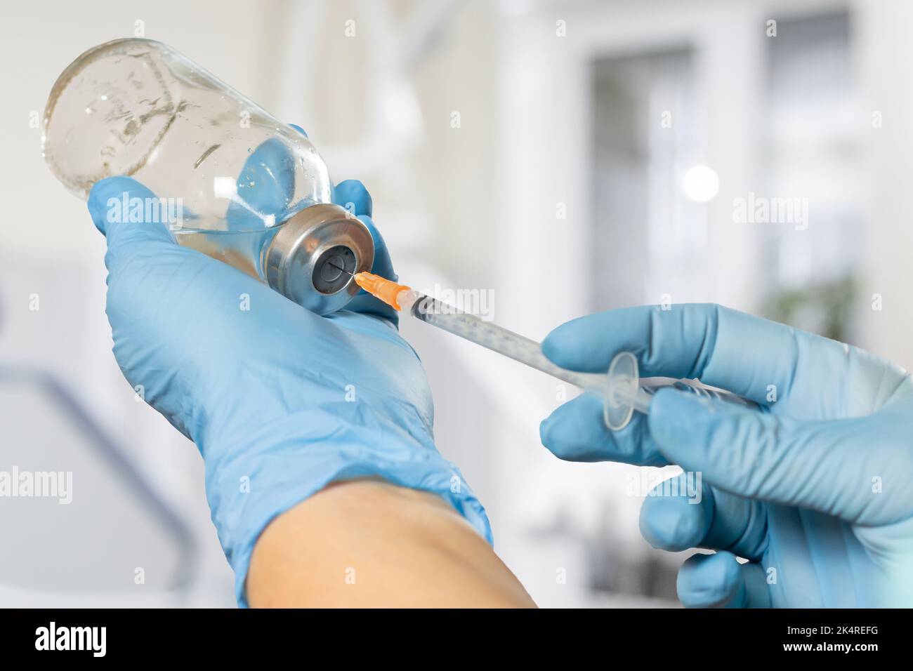 Hands in latex gloves with the glass bottle for liquid medicine and the ...