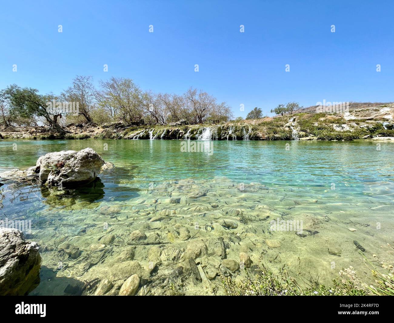 A scenic view of the waterfalls at Wadi Darbat under blue sky in ...