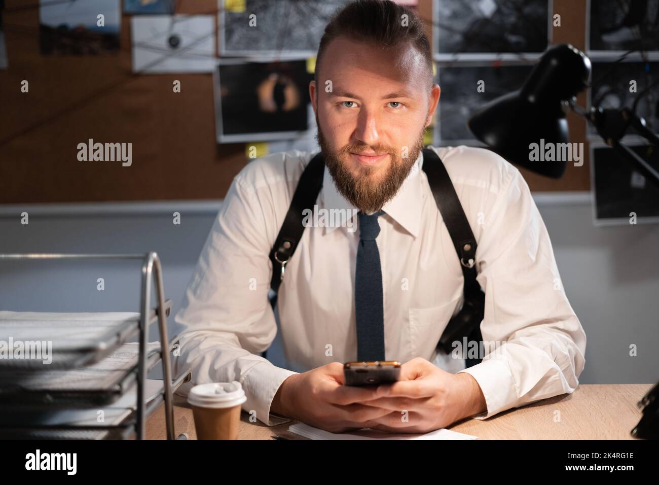 portrait of detective working in office at table with phone, detective ...