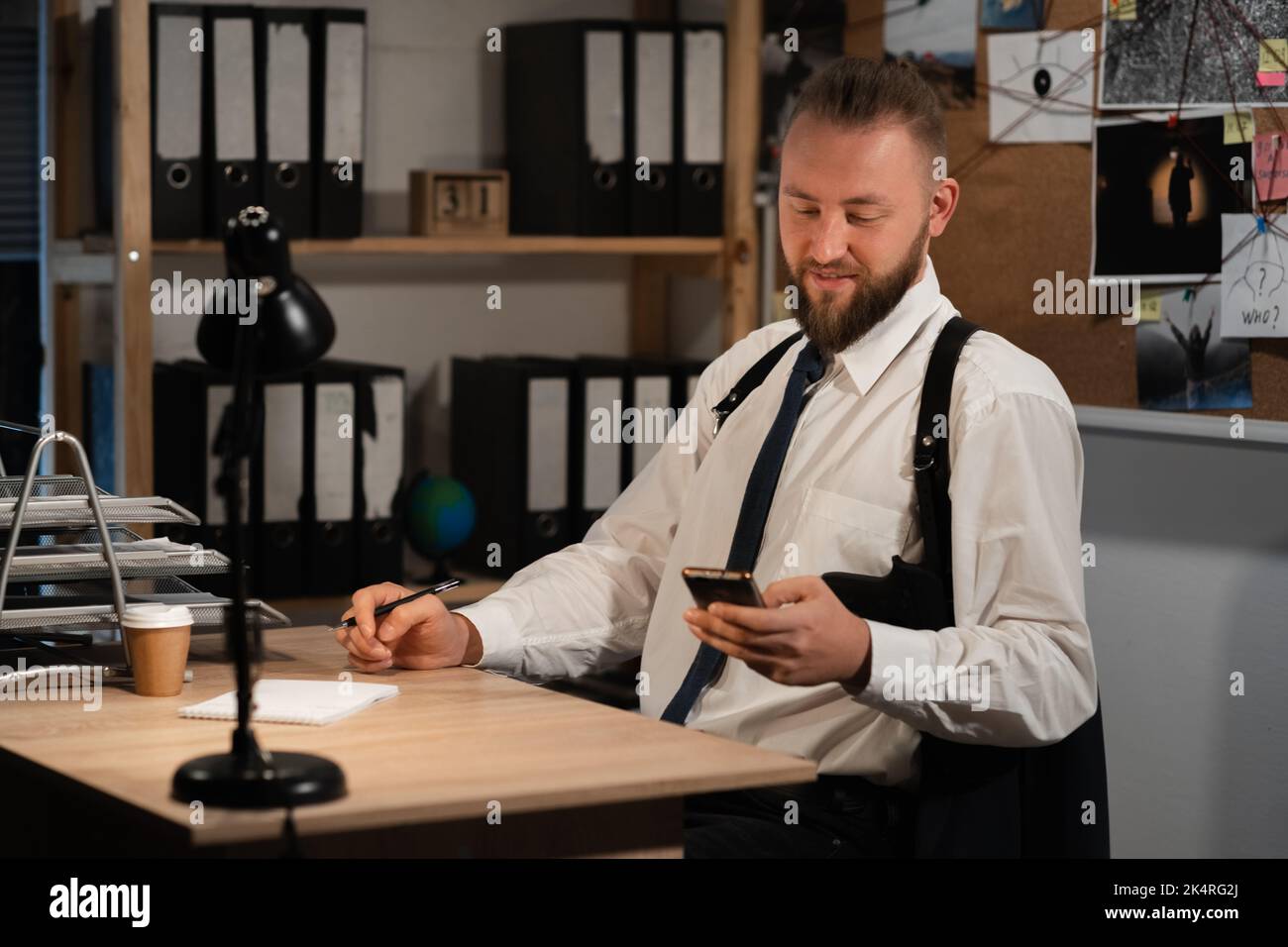 Detective processing evidence in office, working at desk using mobile ...