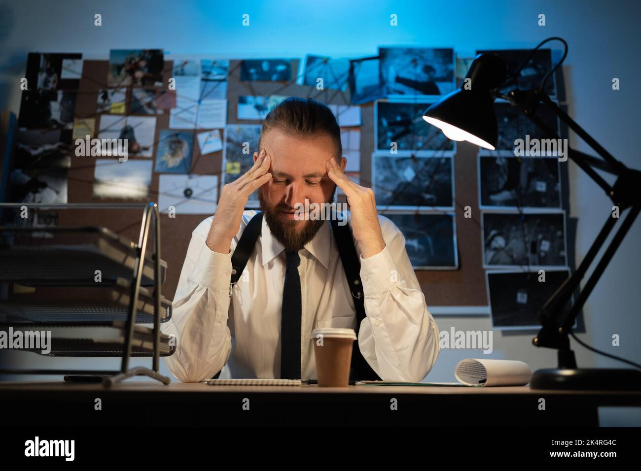 Detective working at desk in his office, thinking on problem, evidence ...