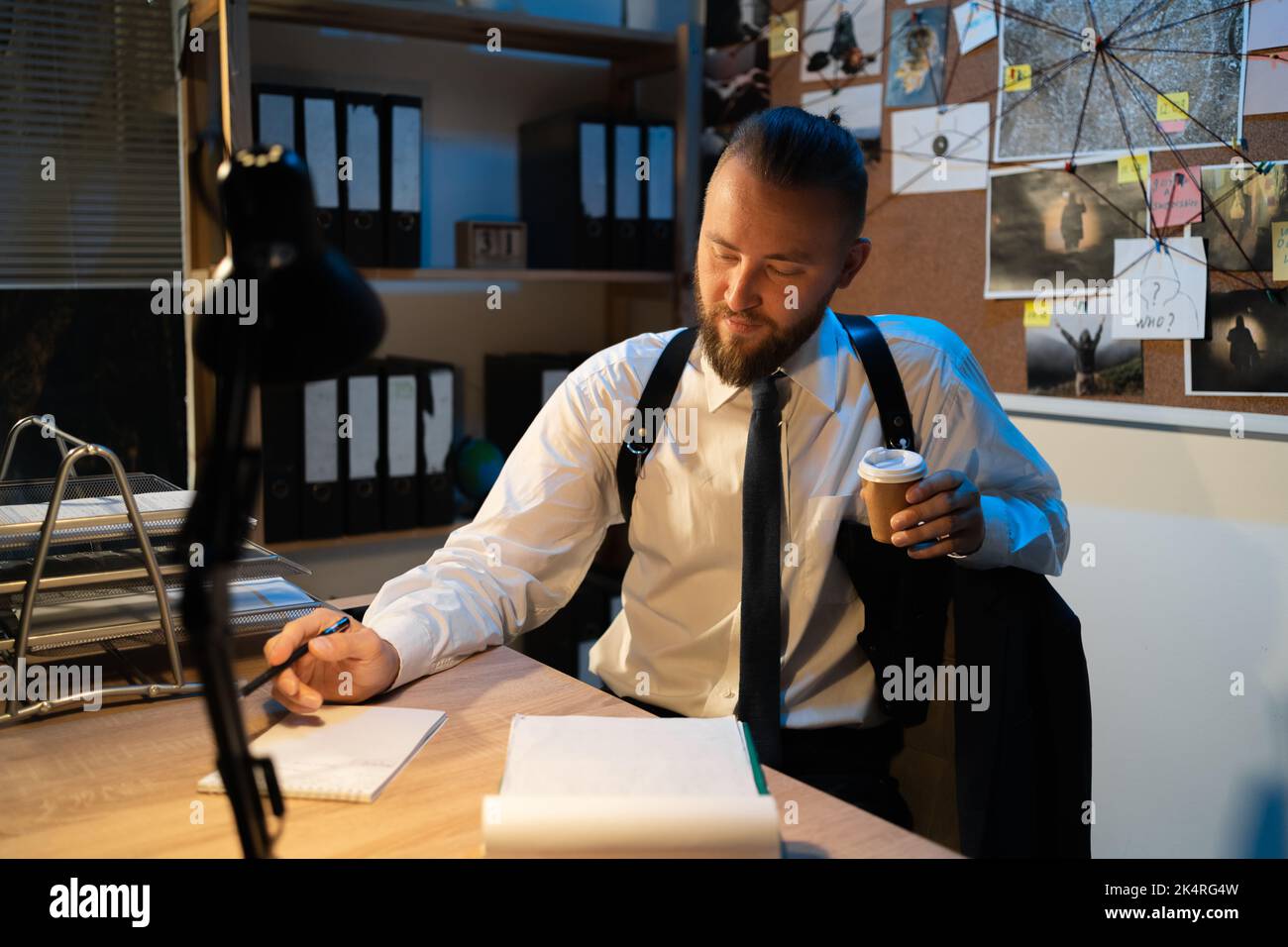 Detective working at desk in his office on workplace with documents ...