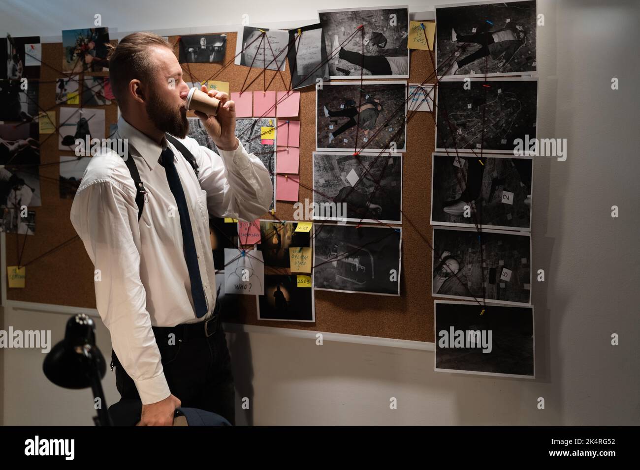 Detective looking at evidence board in office, investigator drinking ...