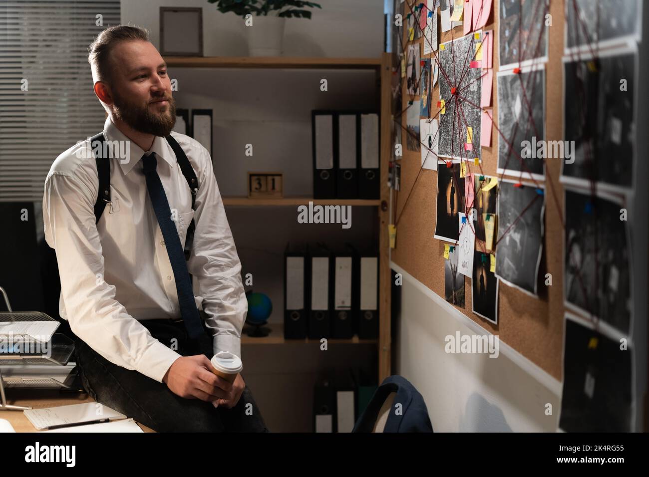 Detective looking at evidence board with photos in office, working at ...
